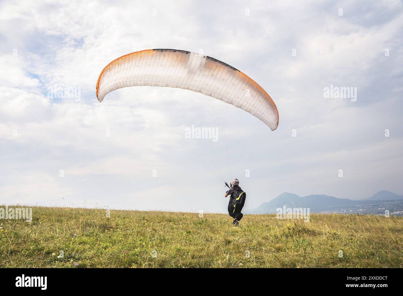 The paraglider opens his parachute before taking off from the mountain ...