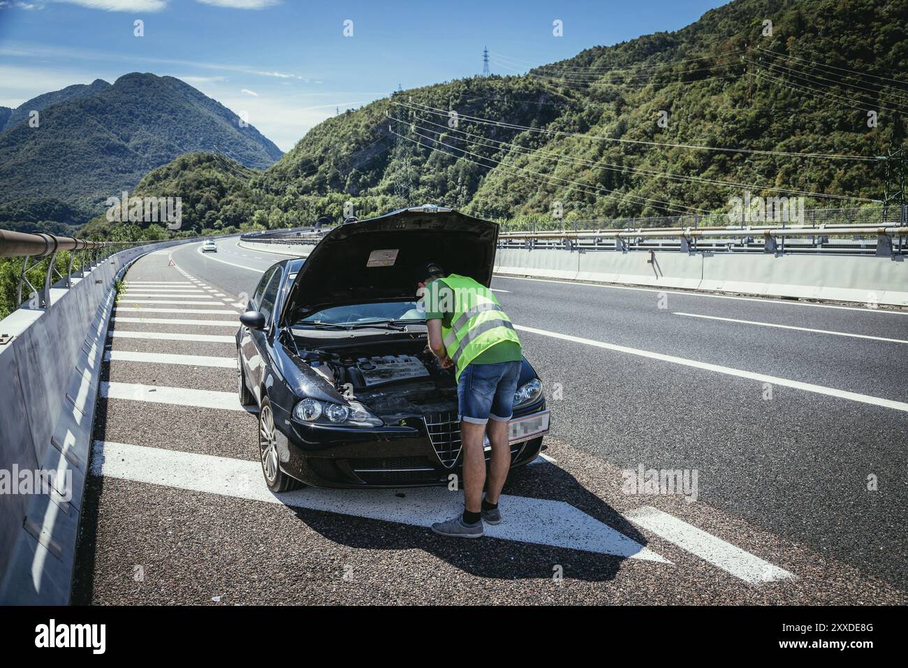 Mechanic in reflective vest is trying to repair a broken-down car on ...