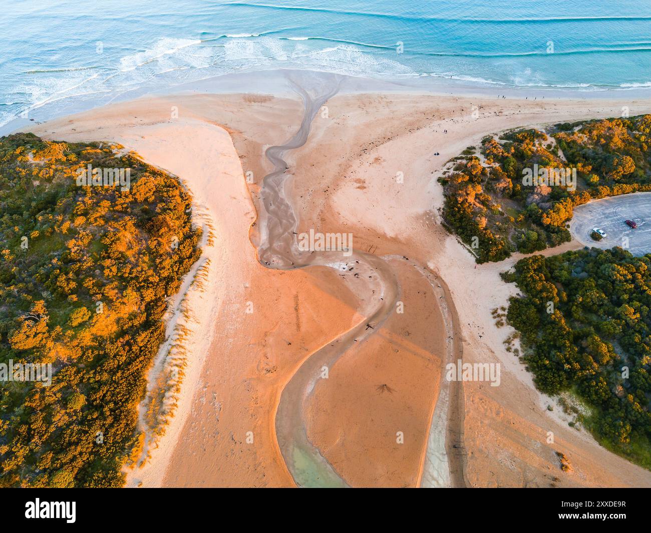Aerial view of a coastal creek winding its way over the beach and out ...