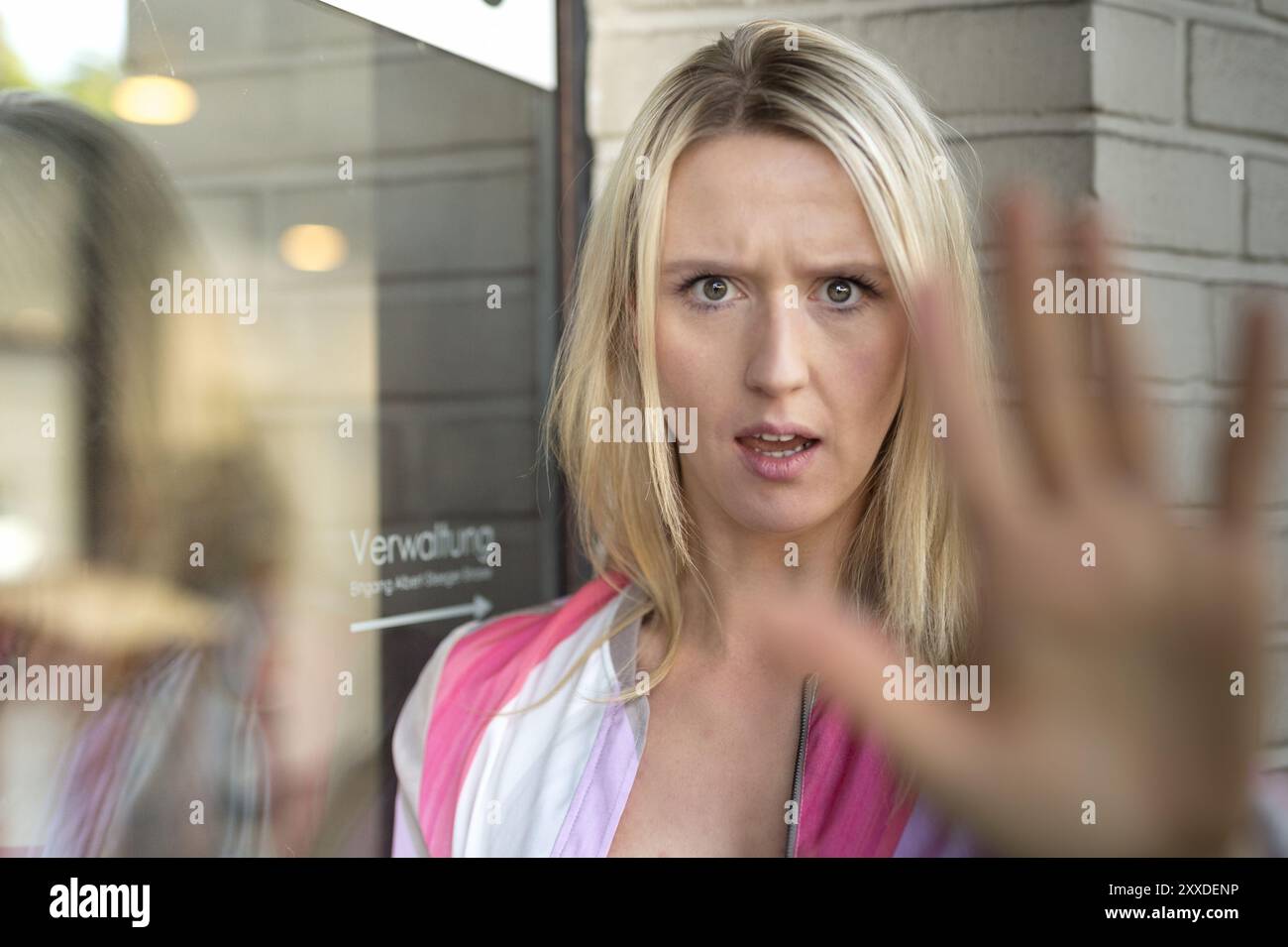 A young woman raises her hand in defence and looks angrily at the ...