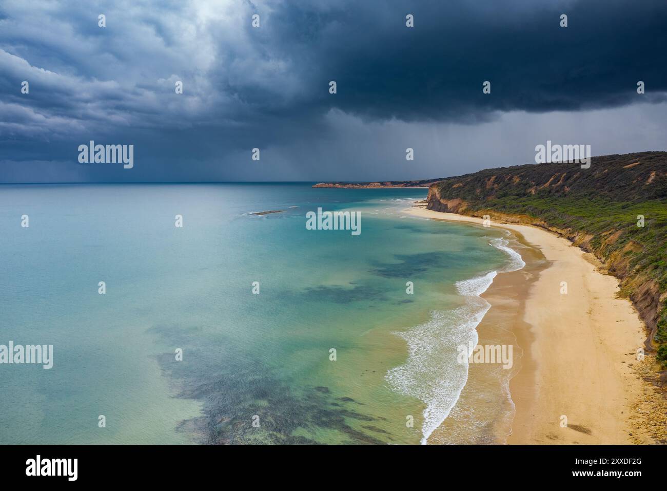 Aerial view of rain falling from dark storm clouds building over a calm ...