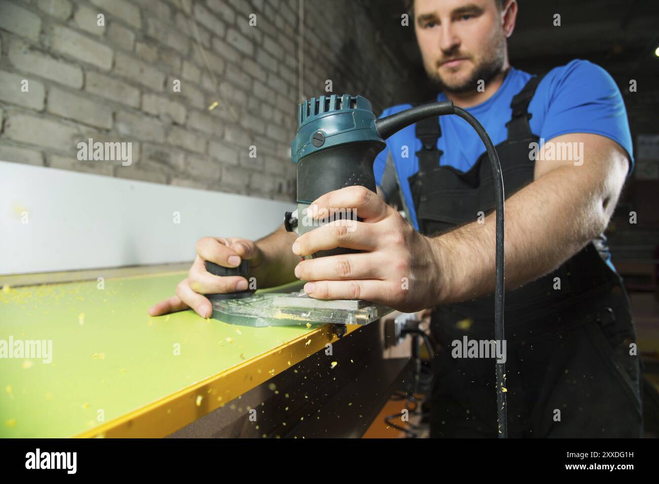 Professional carpenter processes the plastic edges of the countertop ...