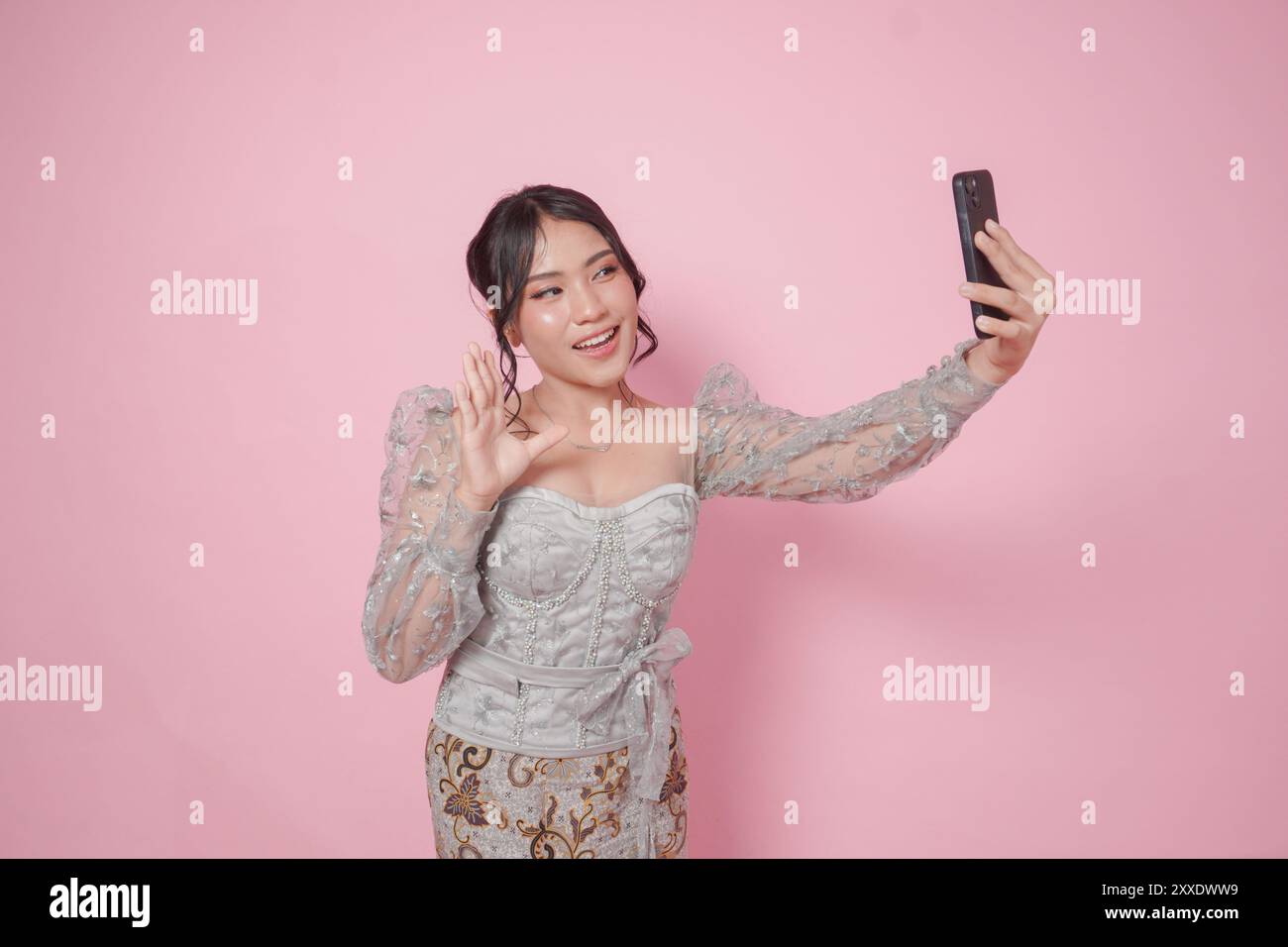Happy Indonesian woman wearing modern kebaya doing video call pose ...