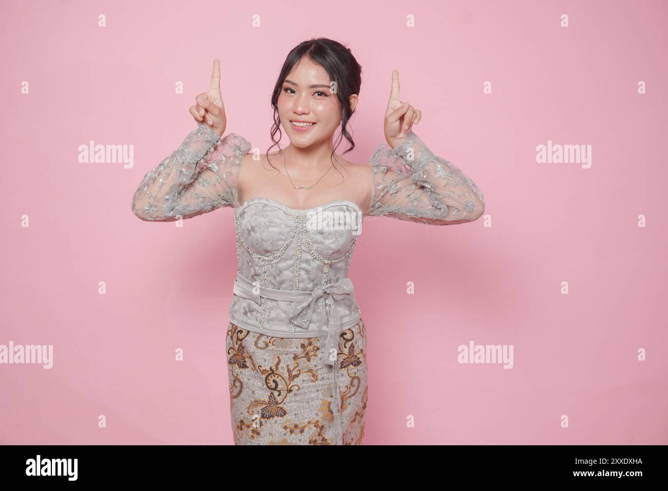 Beatiful Asian woman wearing modern kebaya dress pointing at the copy ...