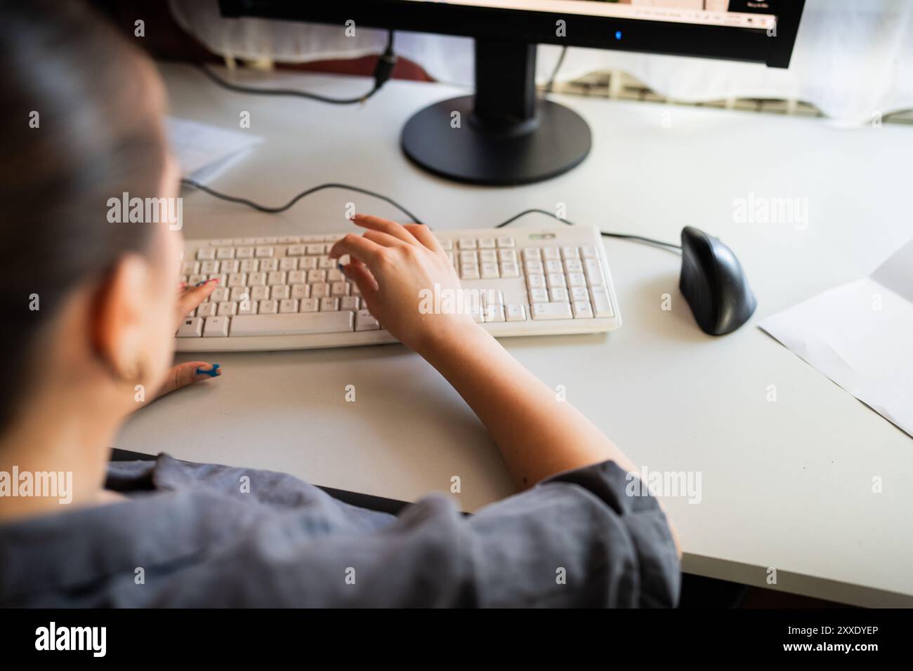 A young woman is sitting at a computer in the office, doing graphic ...