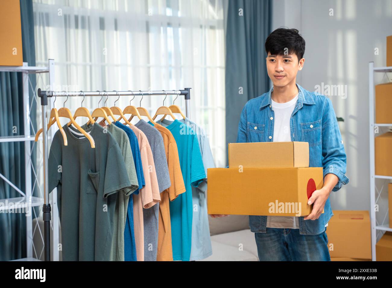 Happy young online seller man holding his packed product boxes to send ...