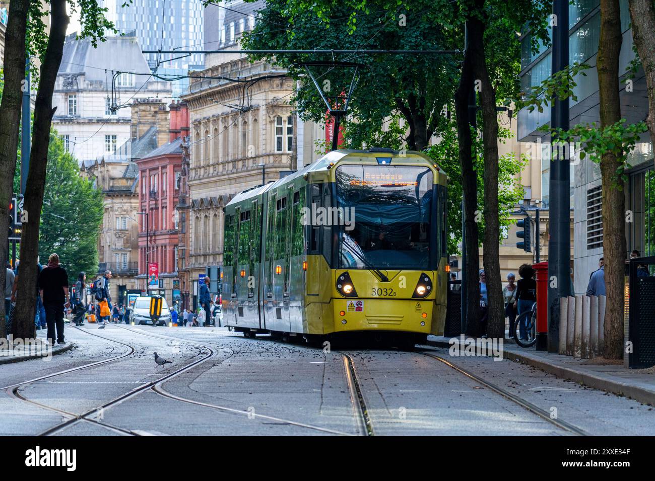 A busy Cross street in Manchester and yellow Metro-Lin Tram passing ...