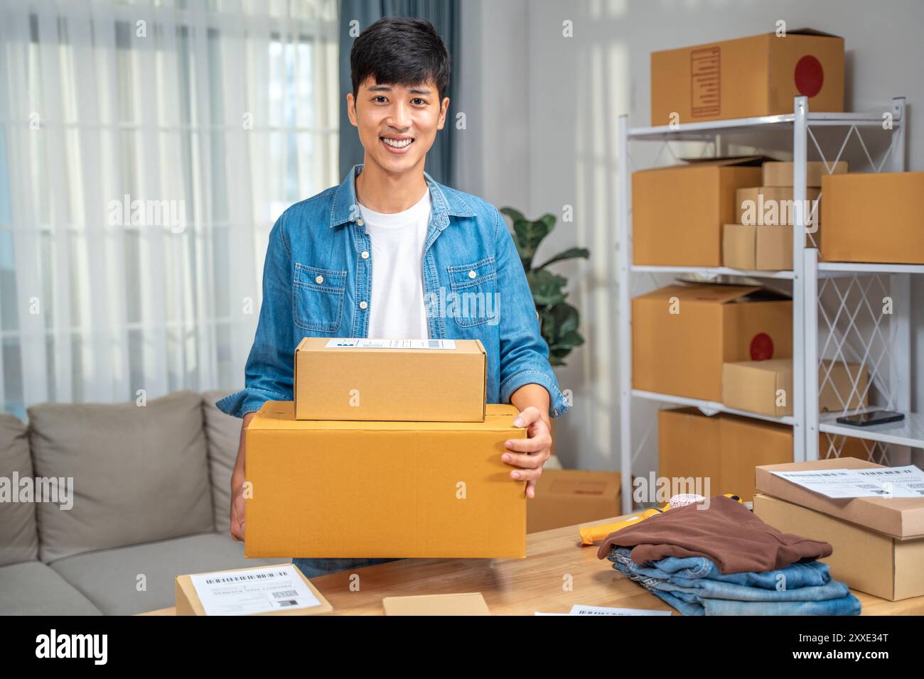 Happy young online seller man holding his packed product boxes to send ...