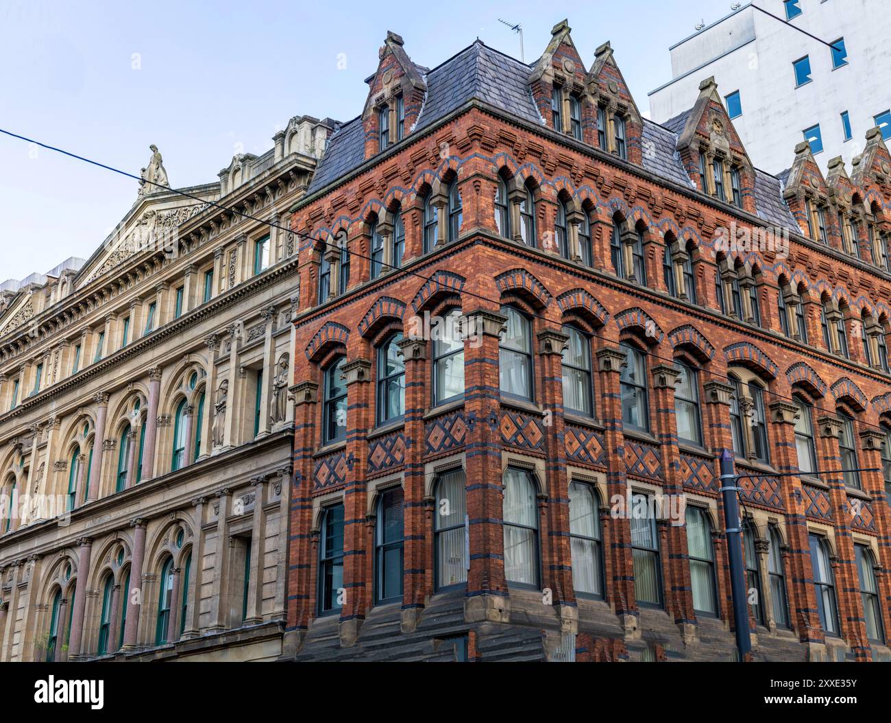 Two adjacent buildings in Manchester, UK.One is made of beige stone and ...