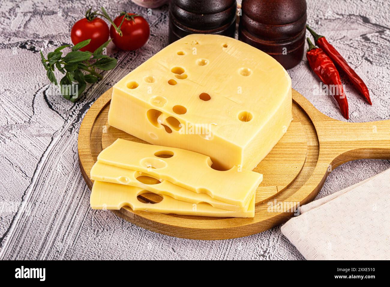Maasdam cheese piece with slices over board Stock Photo - Alamy