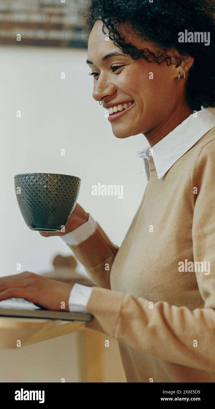 A woman is happily enjoying her coffee while focused on her tasks at a ...