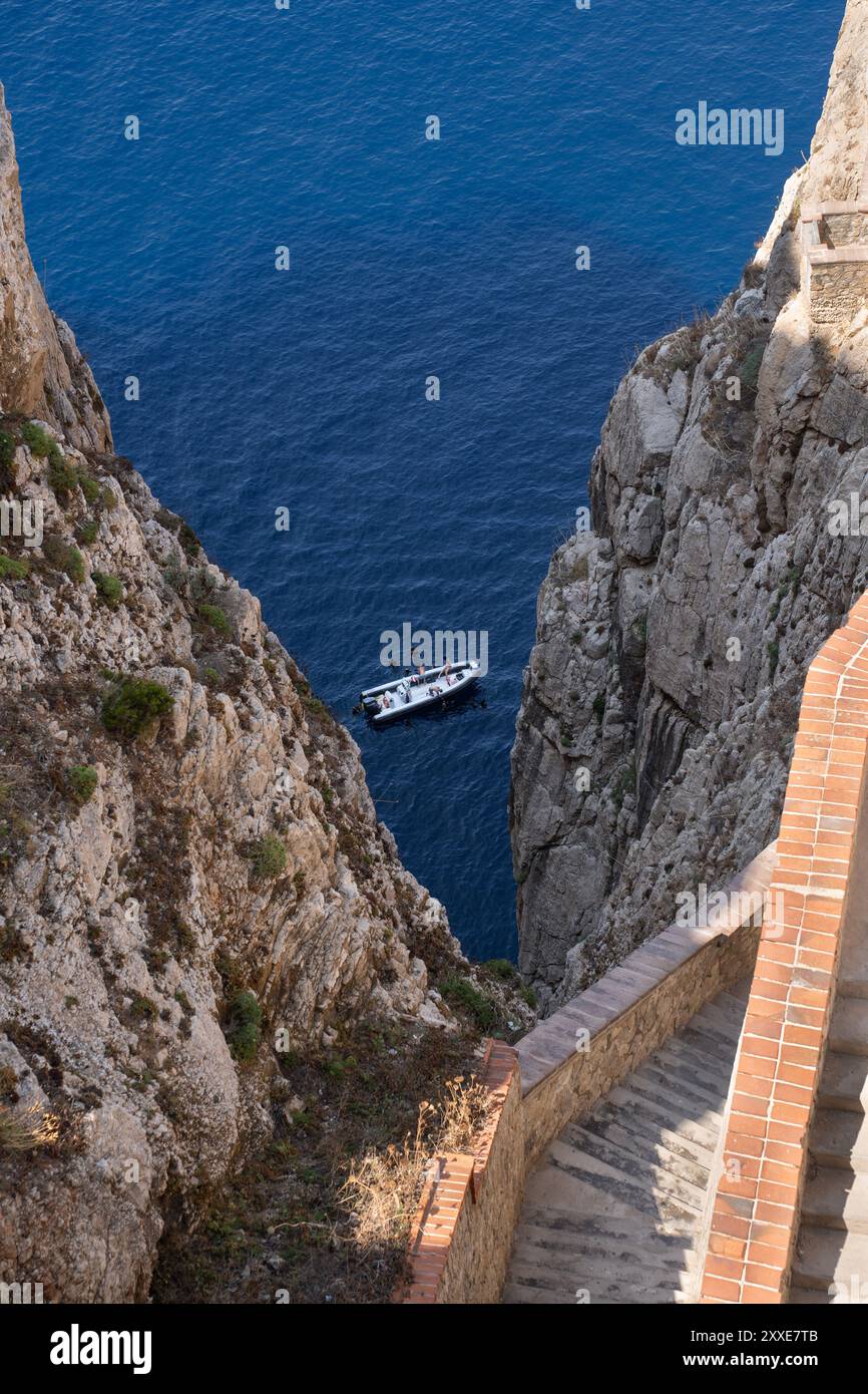 A small boat cruises through the deep blue sea between the rugged ...