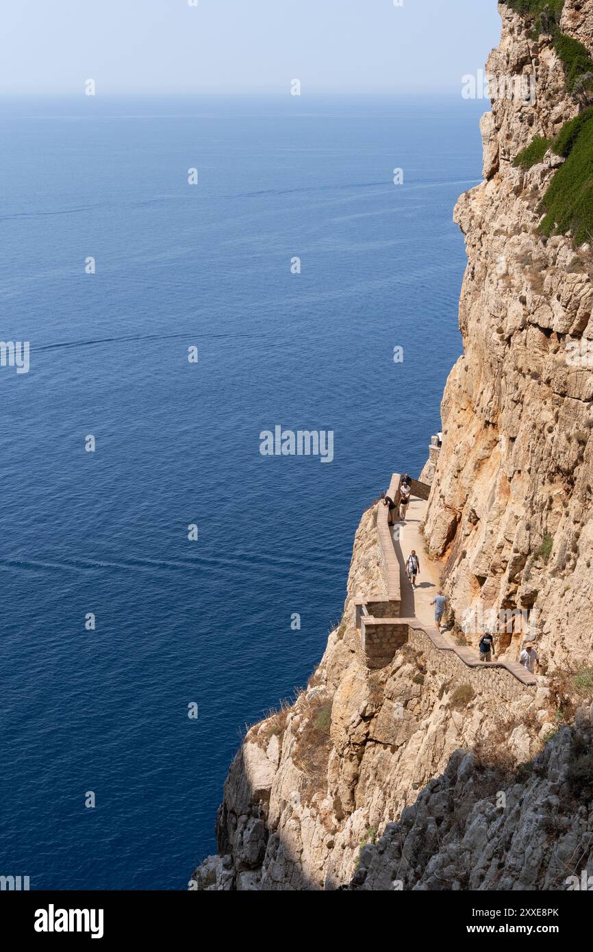 Large cliff with unrecognizable people walking through a corridor dug ...