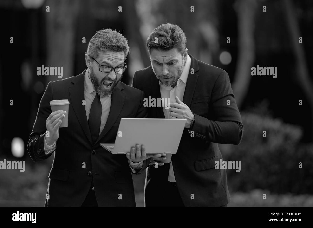 Two businessman using laptop outdoor. Businessmen discussing using ...