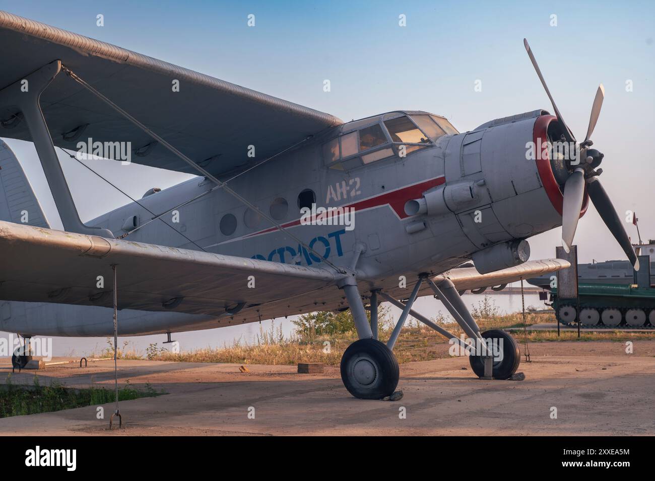 A vintage biplane with Soviet markings parked on an airfield at sunrise ...