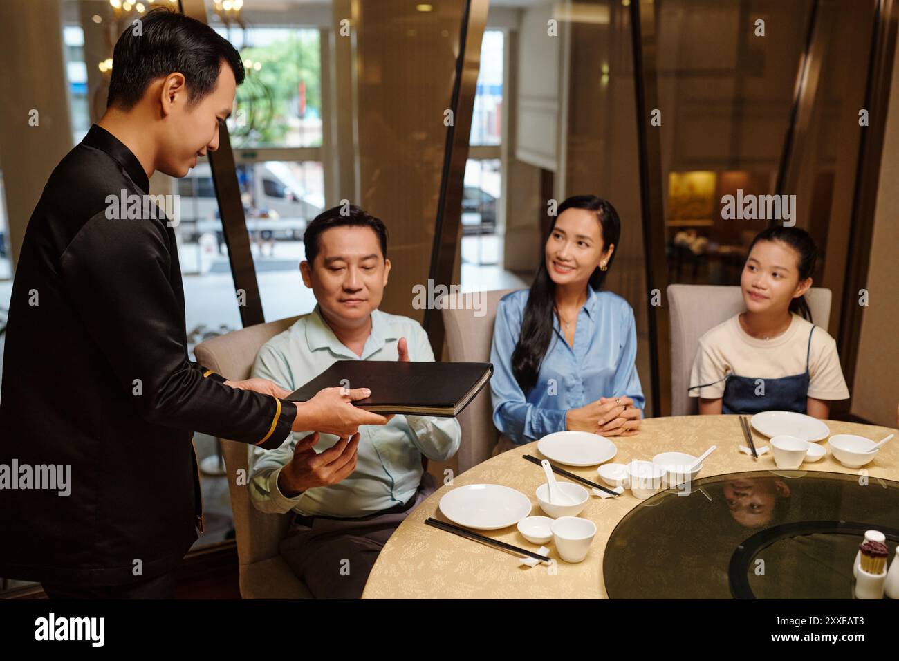 Waiter Giving Menu To Family In The Restaurant Stock Photo - Alamy