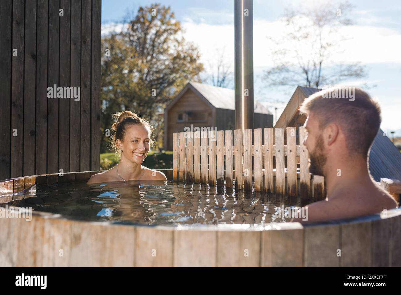 Couple relaxing in a private outdoor wood-fired hot tub, enjoying ...