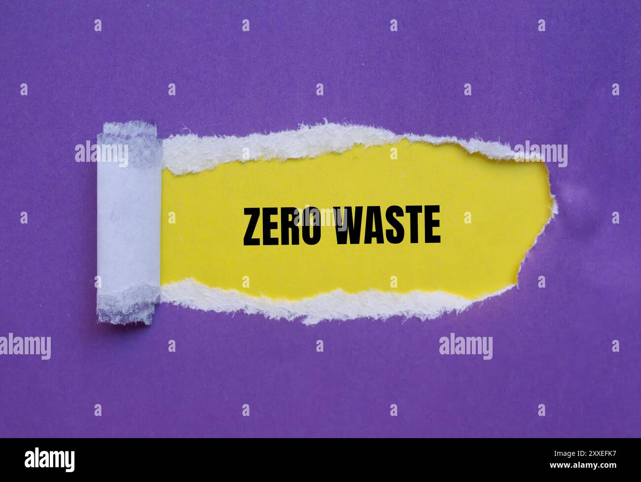 Zero waste message written on ripped torn purple paper with yellow background. Conceptual zero ...