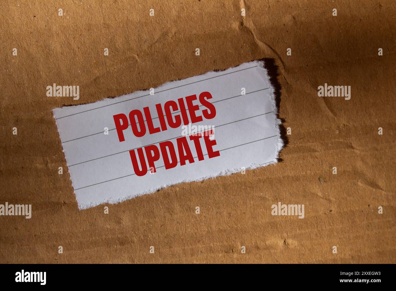 Policies update message written on ripped torn white paper piece with cardboard background ...