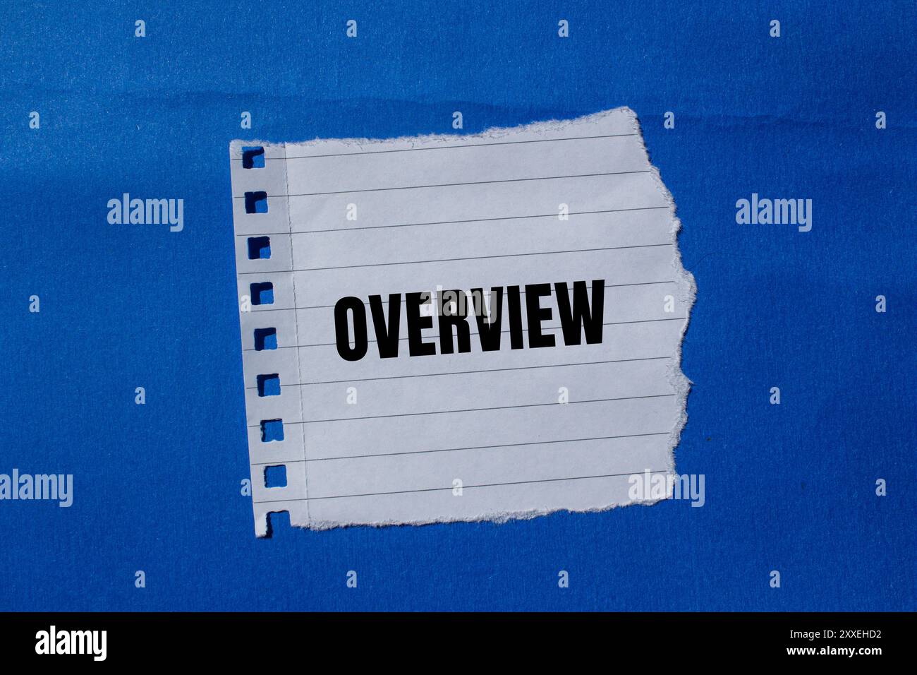 Overview message written on ripped torn paper piece with blue ...