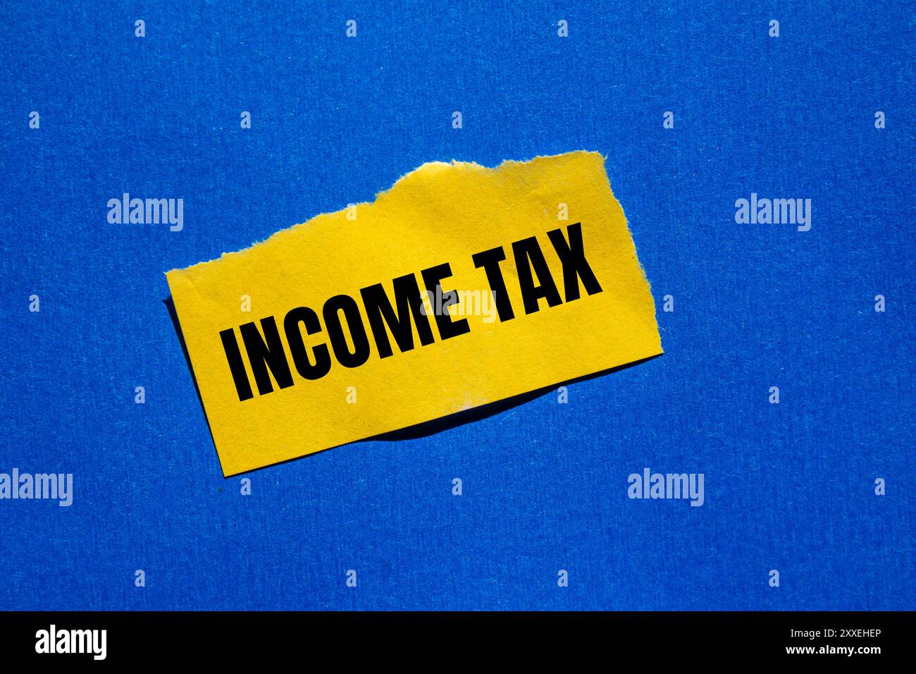 Income tax message written on ripped torn yellow paper piece with ...