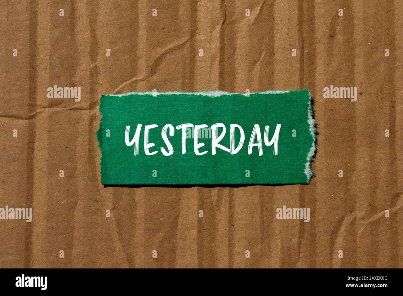 Yesterday word written on ripped torn green paper piece with cardboard ...