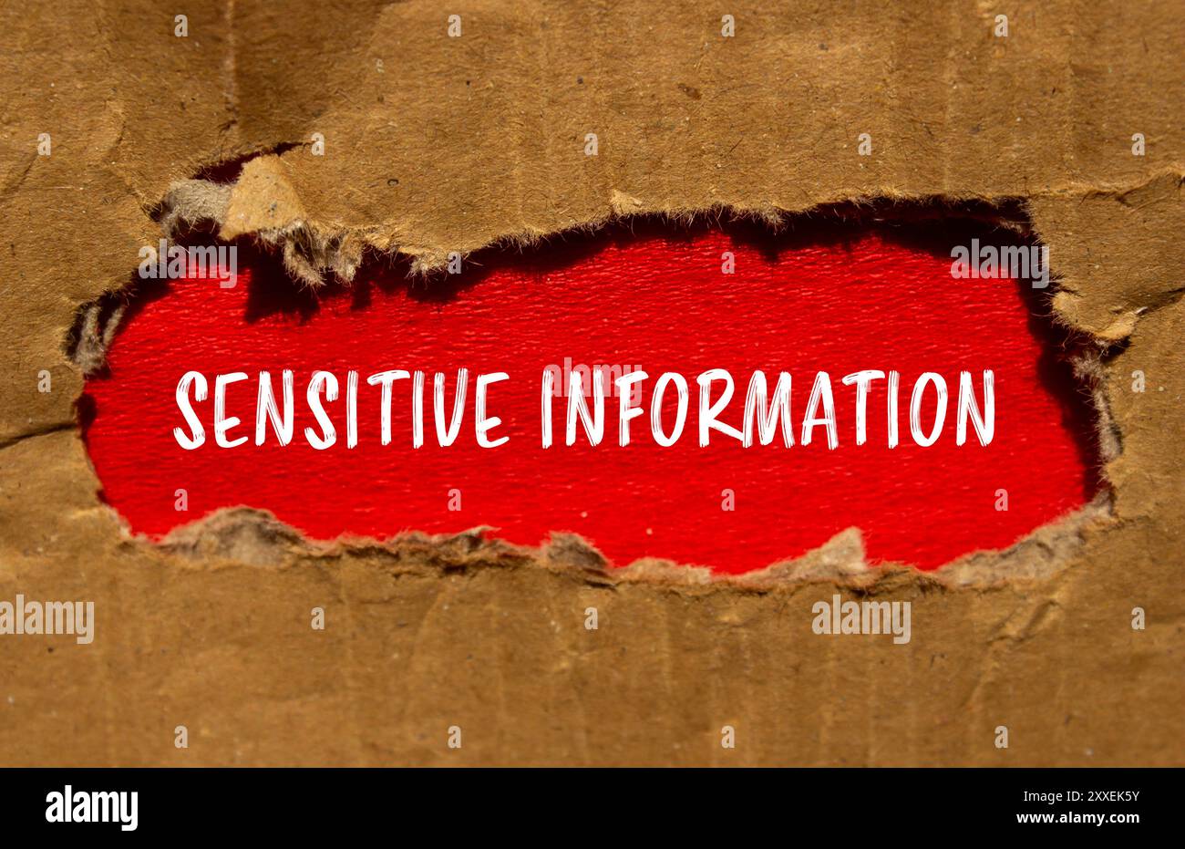 Sensitive information message written on torn cardboard paper with red ...