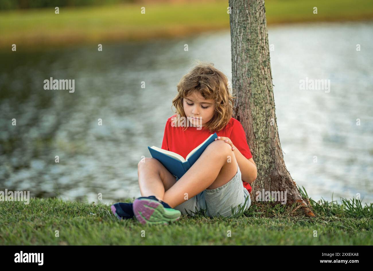 Cute kid reading book on meadow outdoors. School and education. Nature ...