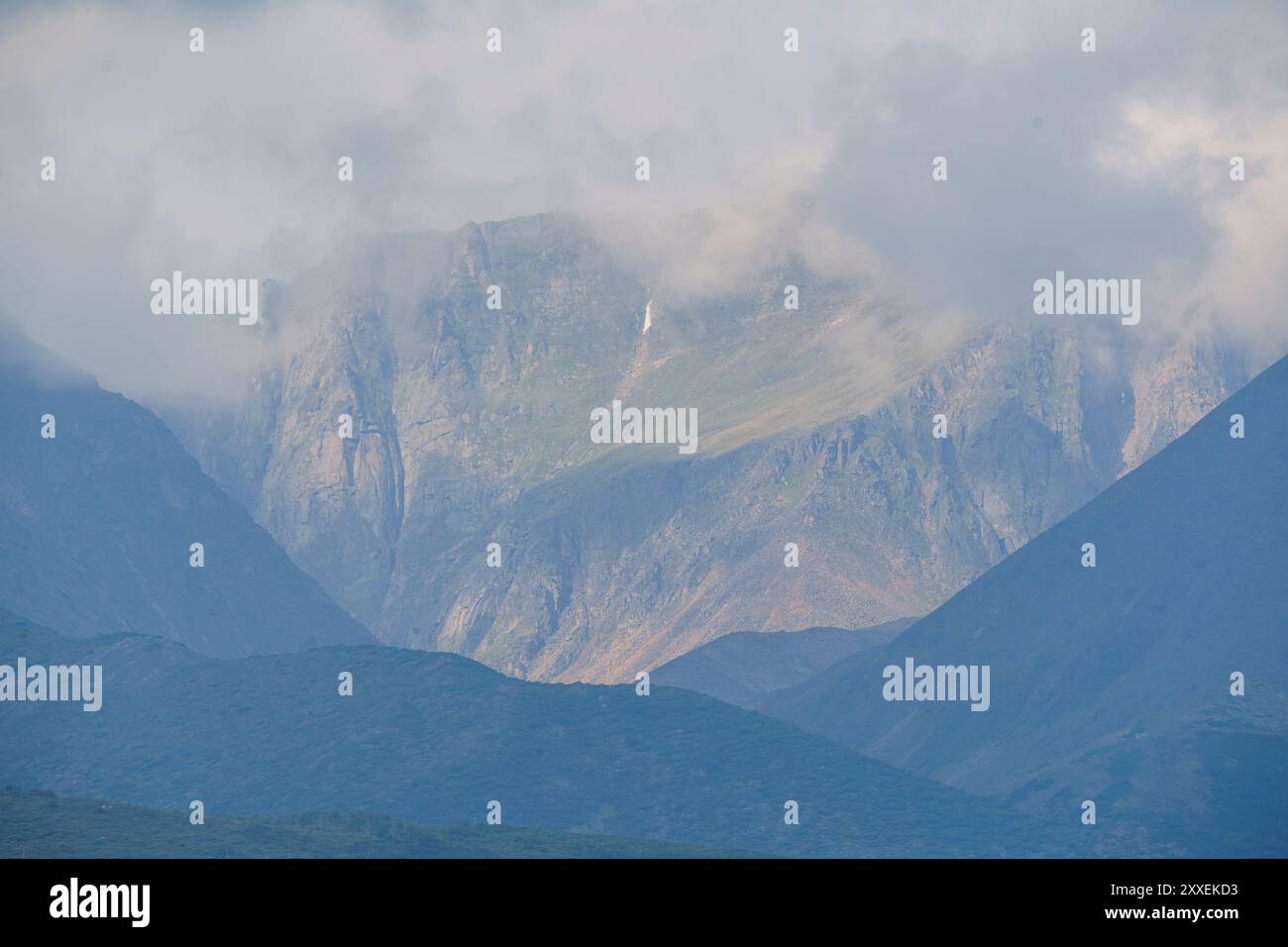 A view of misty mountain peaks partially obscured by clouds, creating a ...
