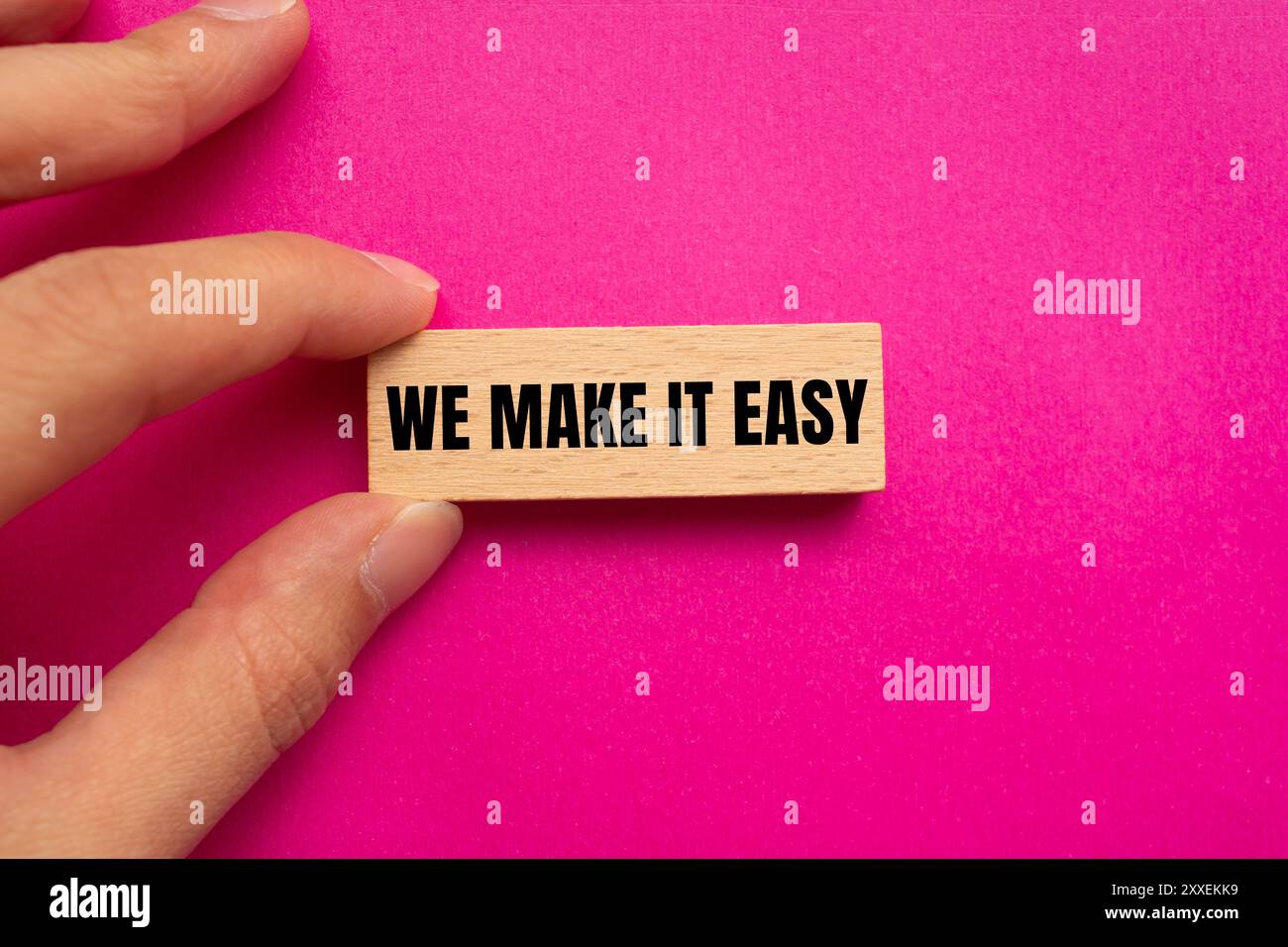 We make it easy message written on wooden block with pink background ...