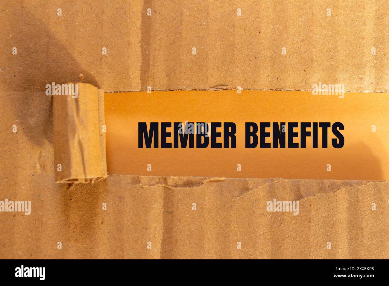 Member benefits message written on ripped torn cardboard paper with orange background ...