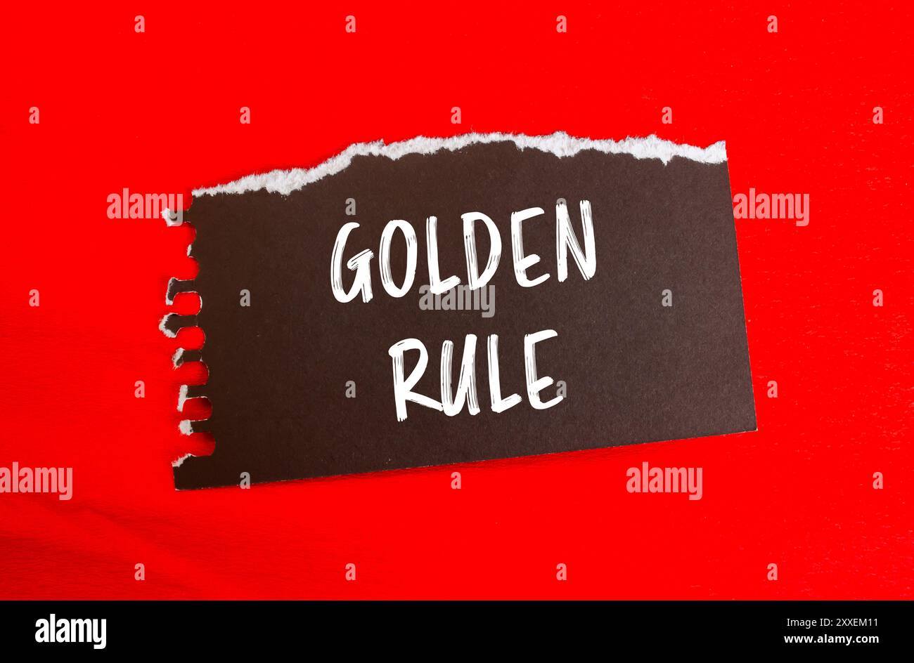 Golden rule message written on ripped torn black paper piece with red ...