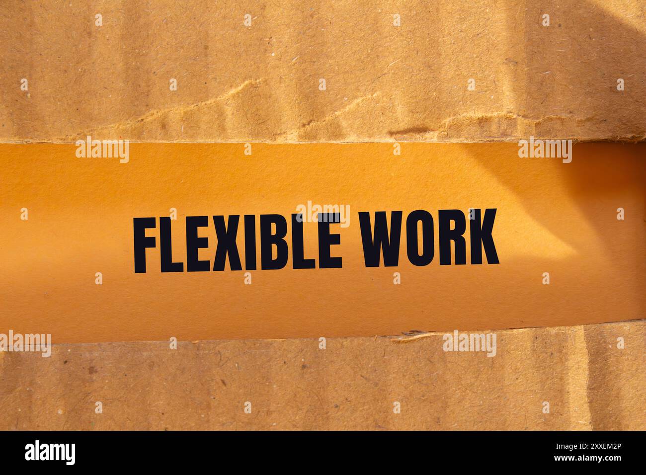Flexible work message written on ripped torn cardboard paper with orange background. Conceptual ...