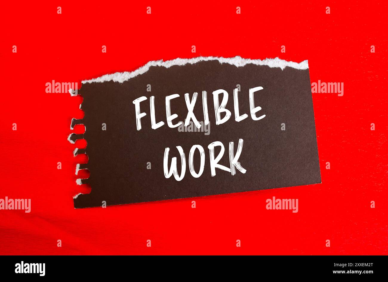 Flexible work message written on ripped torn black paper piece with red background. Conceptual ...