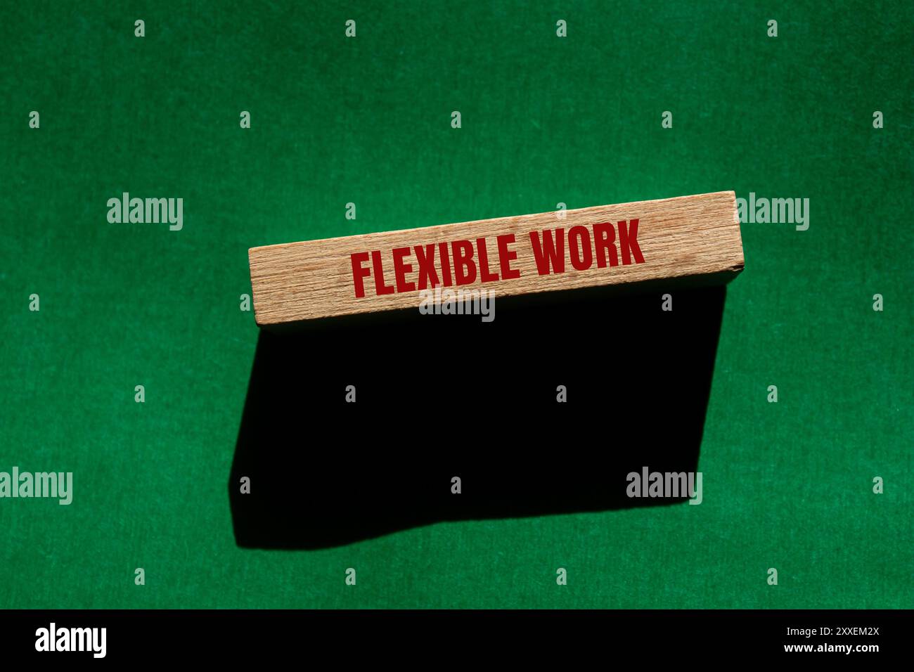 Flexible work message written on wooden block with green background ...