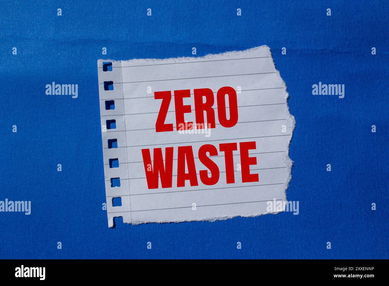 Zero waste message written on ripped torn paper piece with blue background. Conceptual zero ...