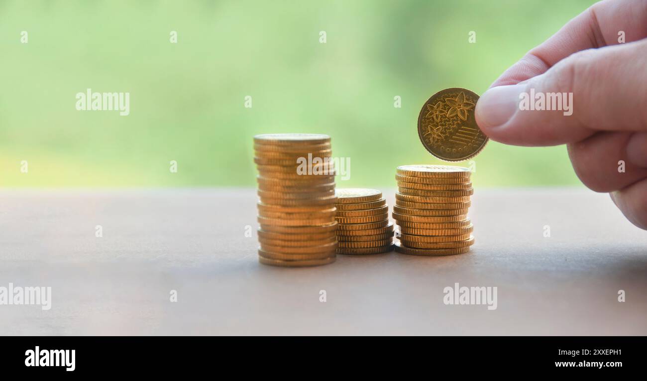 Hand putting coins on a stacking coins. Wealth and copy space concept ...
