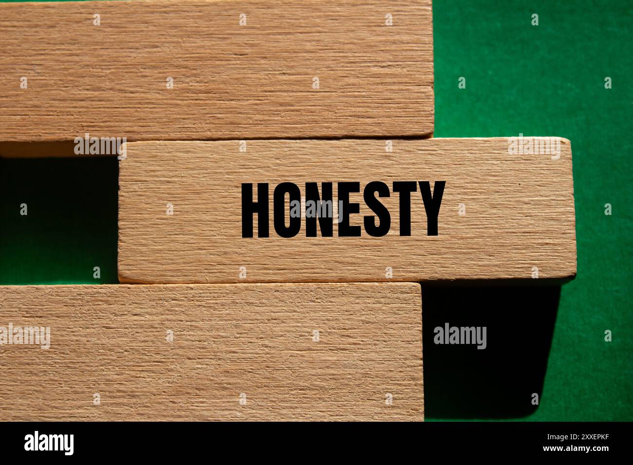 Honesty message written on wooden block with green background ...