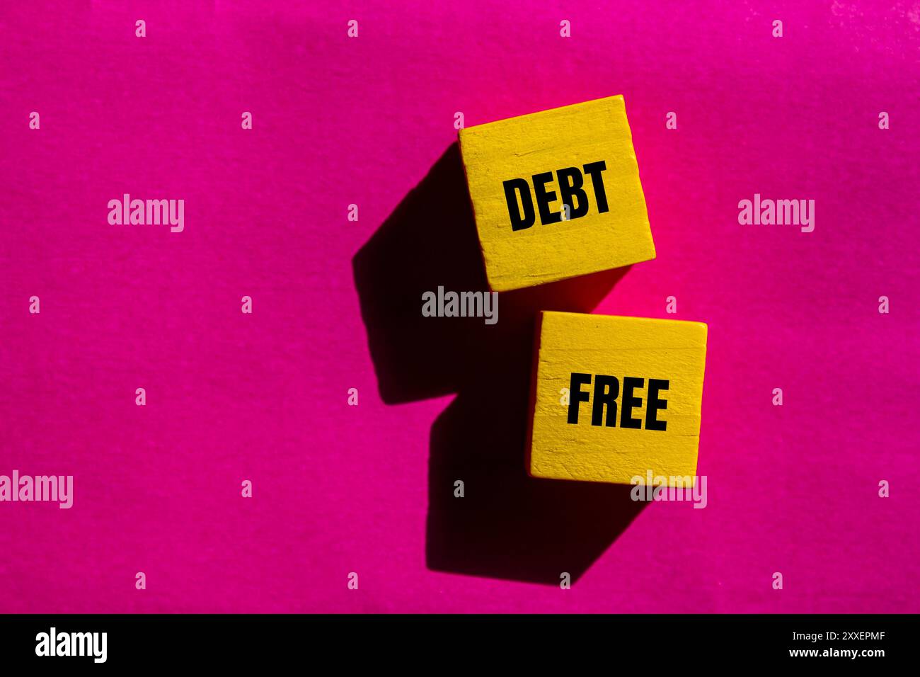 Debt free message written on yellow wooden cubes with pink background ...