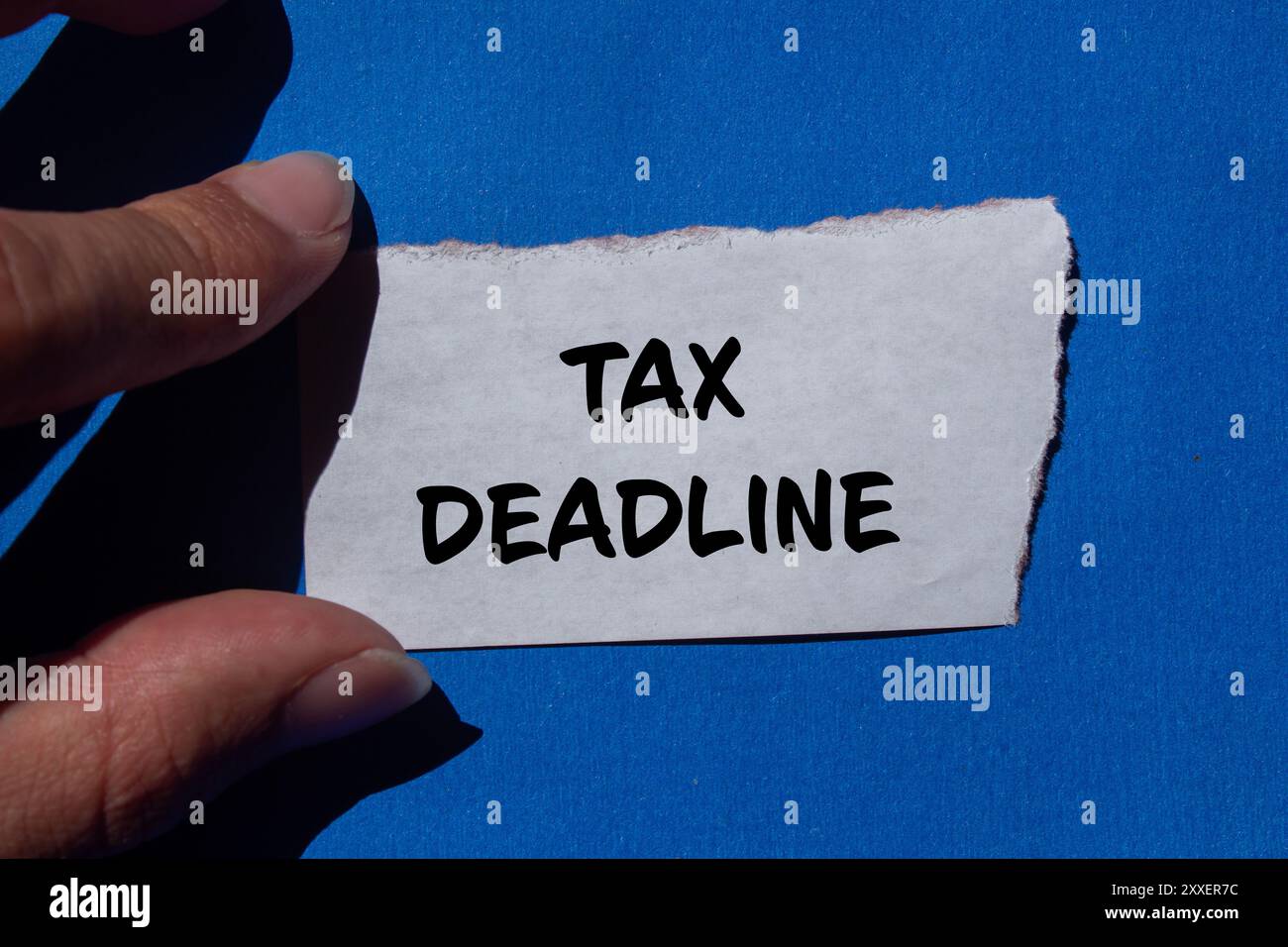 Tax deadline message written on ripped torn paper with blue background ...