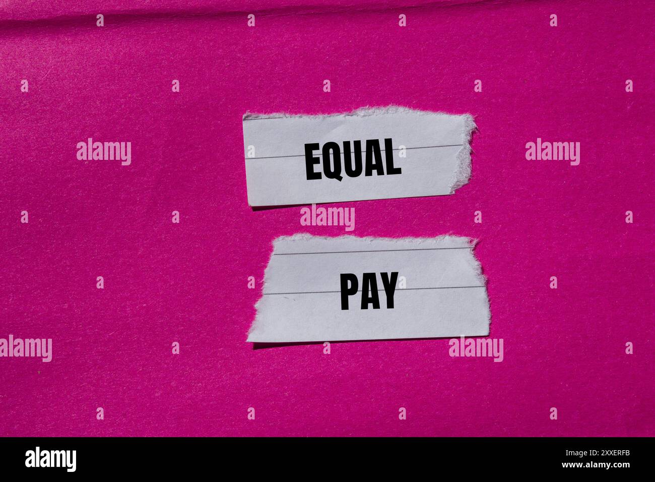 Equal pay message written on ripped torn paper pieces with pink ...