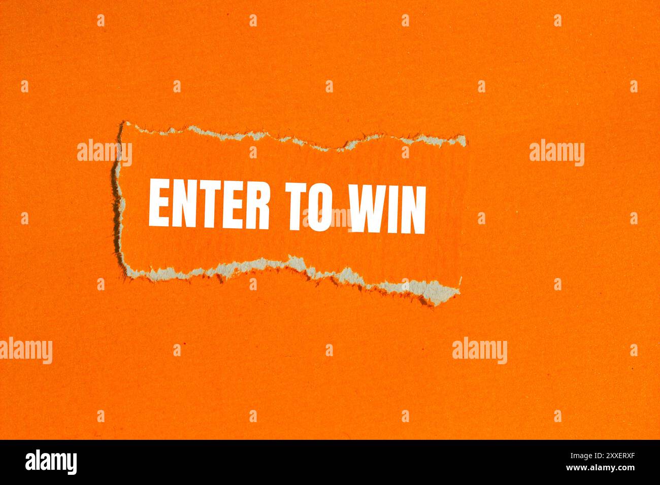 Enter to win message written on ripped torn orange paper with orange background. Conceptual ...