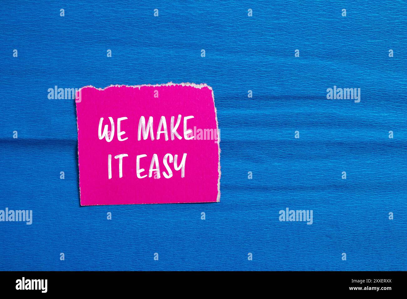 We make it easy message written on ripped torn pink paper piece with blue background. Conceptual ...