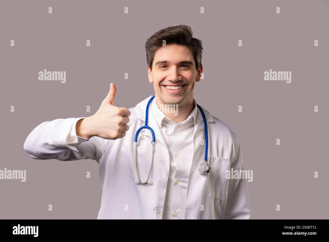 Doctor showing thumb up sign on white background. Positive young man in ...