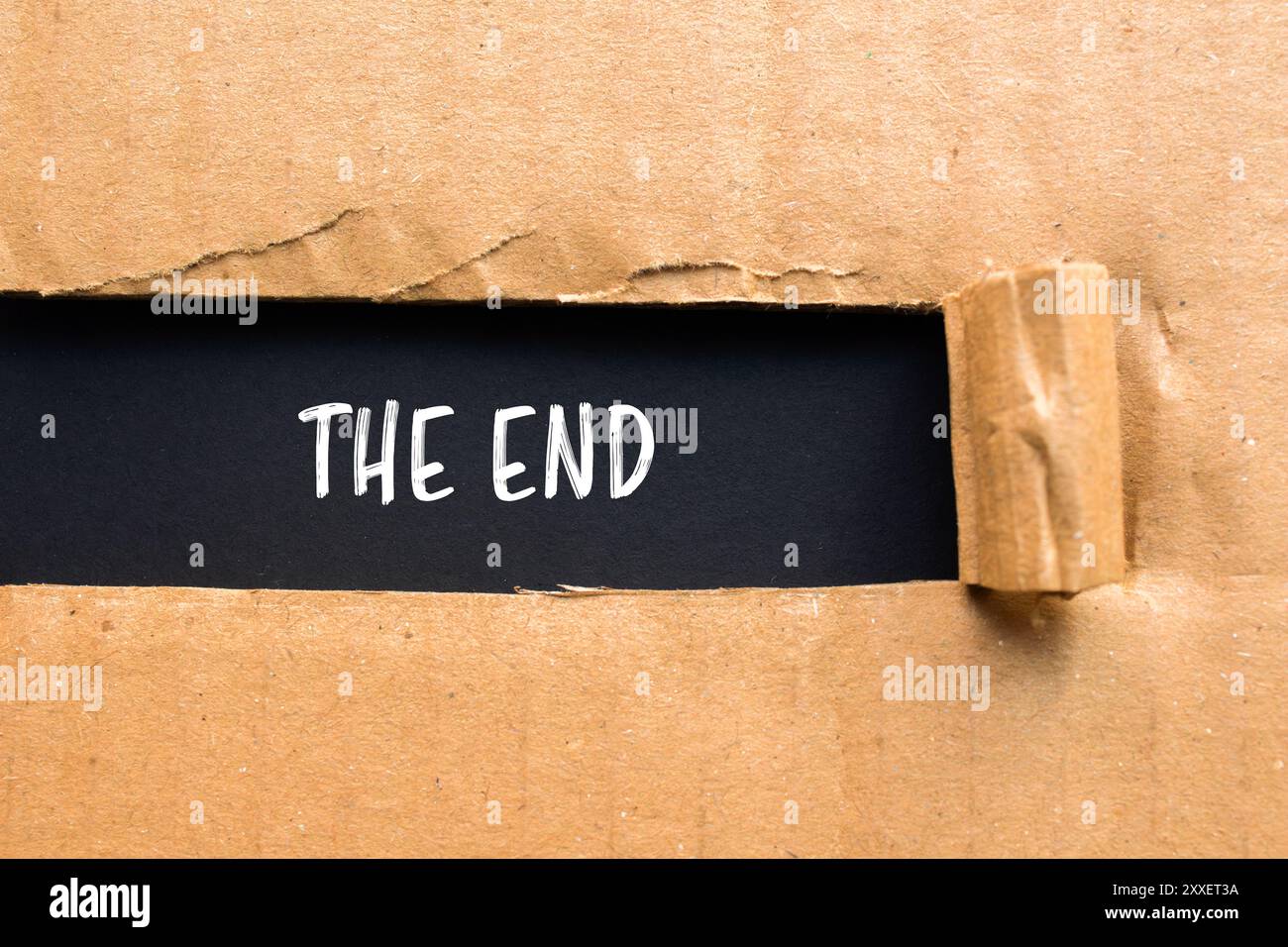 The end message written on ripped torn cardboard paper with black background. Conceptual the end ...