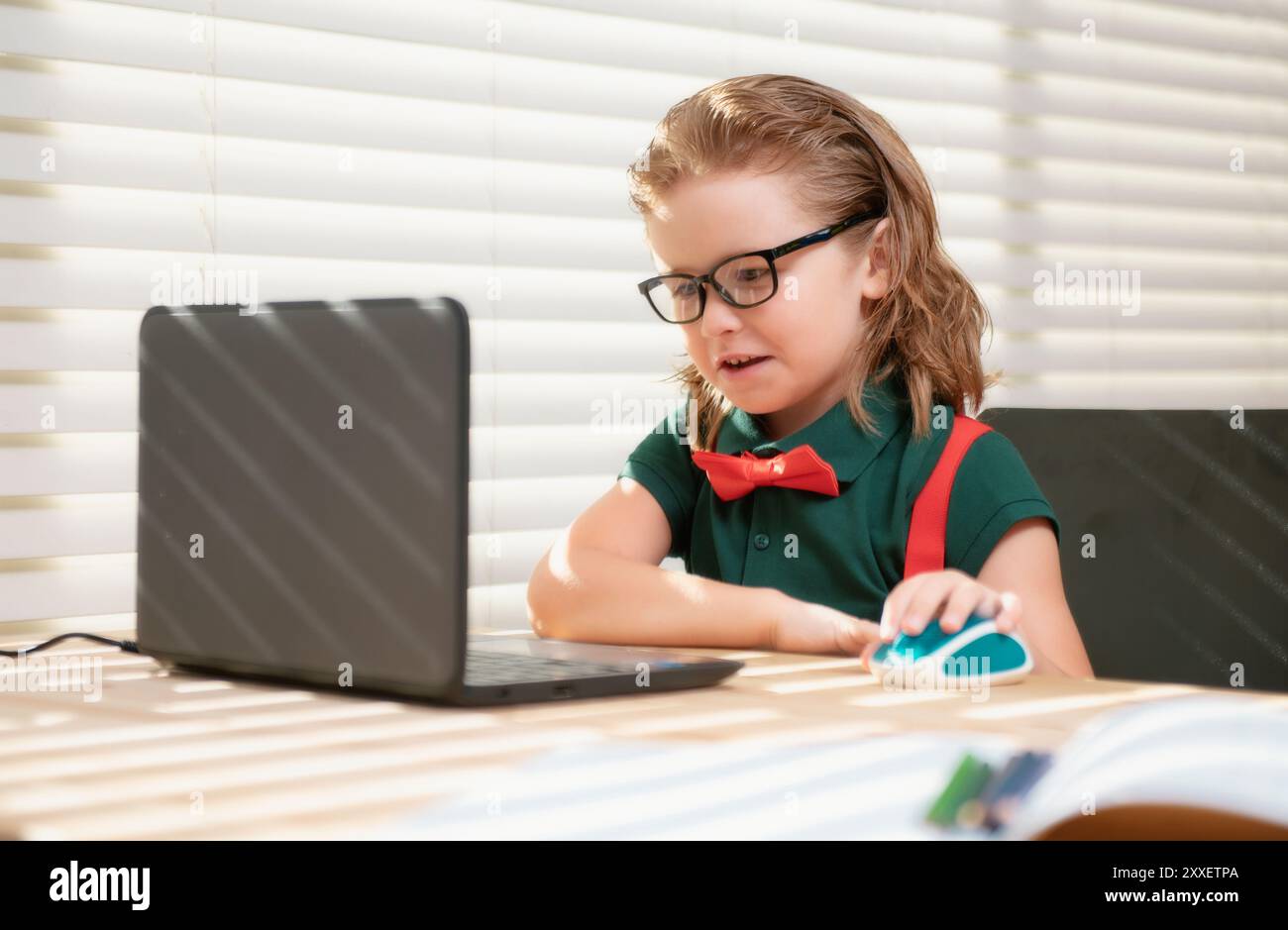 Child boy using a laptop and study online lesson. Pupil at school. Cute ...