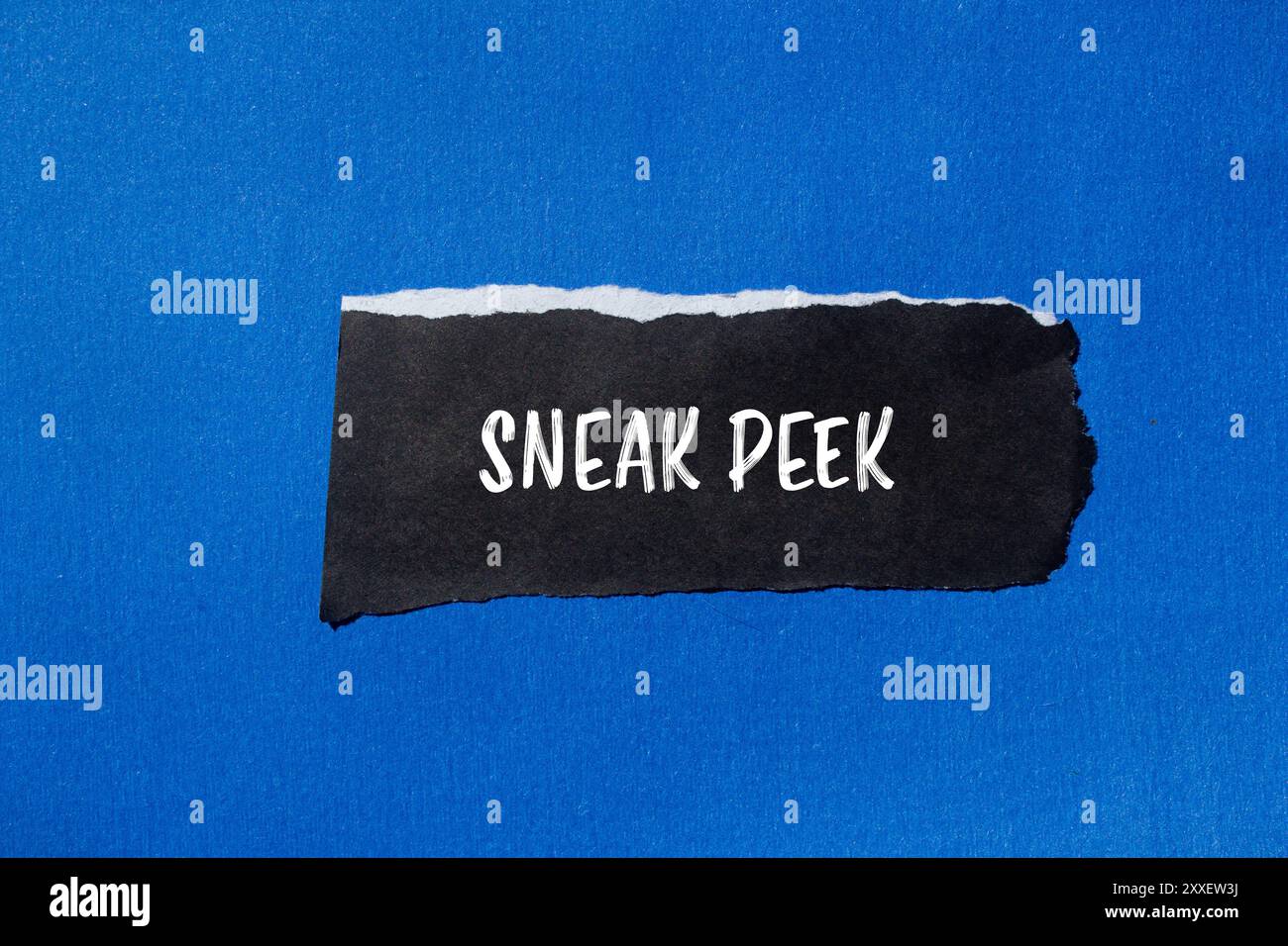 Sneak peek message written on ripped torn black paper piece with blue ...