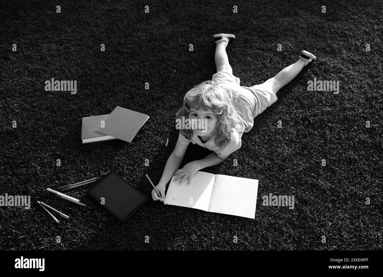 Kid boy reading interest book and writing on notebook in the garden ...