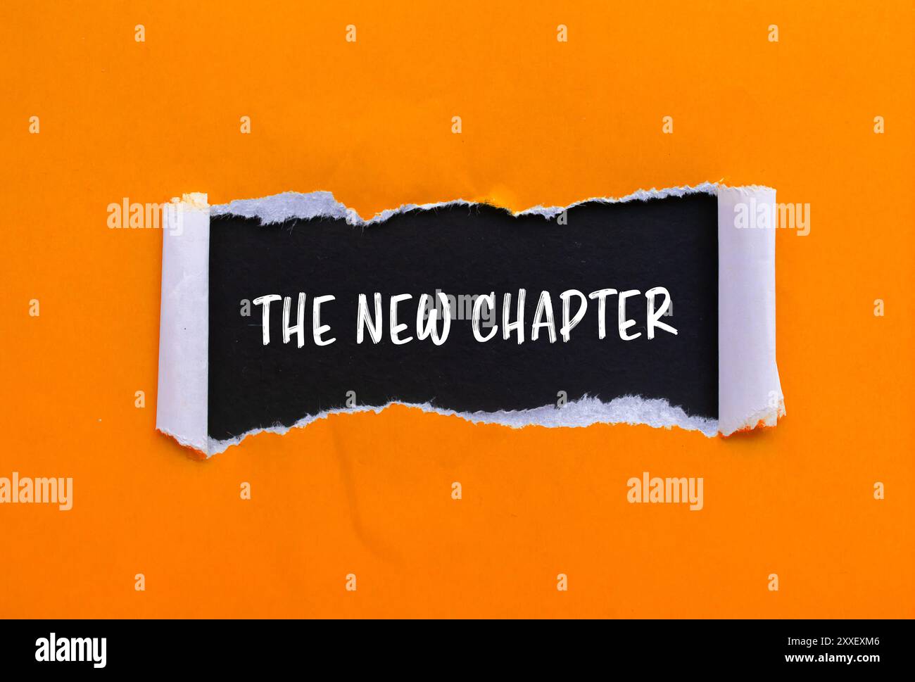 The new chapter message written on ripped torn orange paper with black background. Conceptual ...