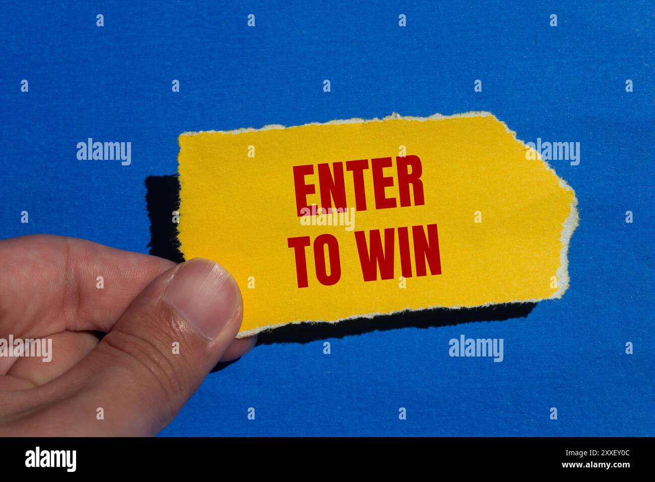 Enter to win message written on ripped torn yellow paper with blue ...